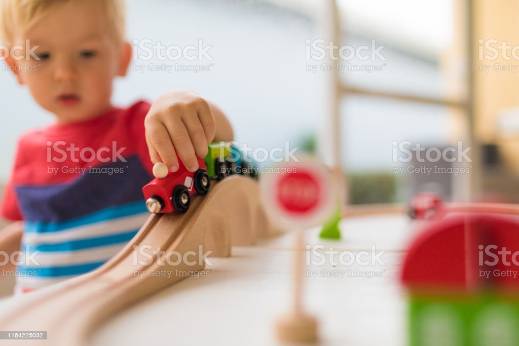 Little boy playing with wooden toy train. – Blossom Play Cafe